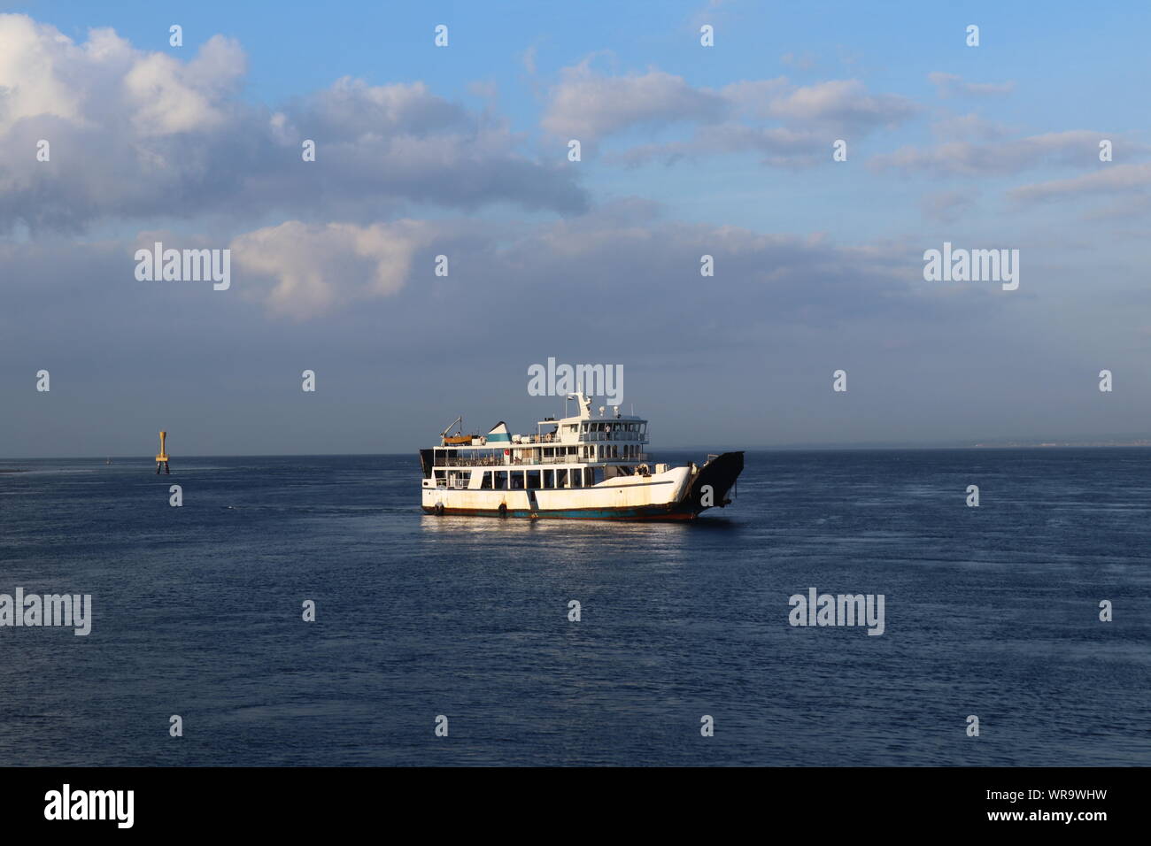Large ferryboat carrying passengers and cars crossing in blue sea ...