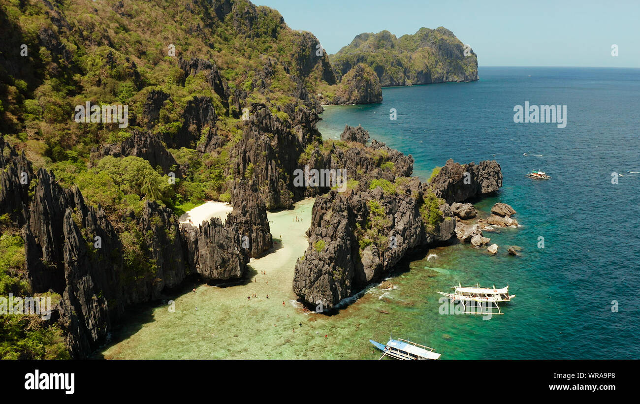 Tropical lagoon with sandy beach surrounded by cliffs. El nido ...