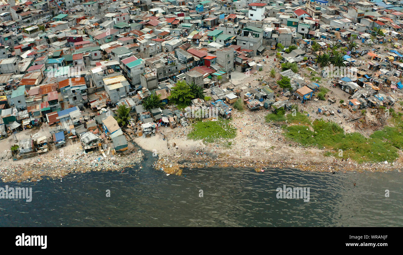 Slums near the port in Manila on the bank of a river polluted with ...