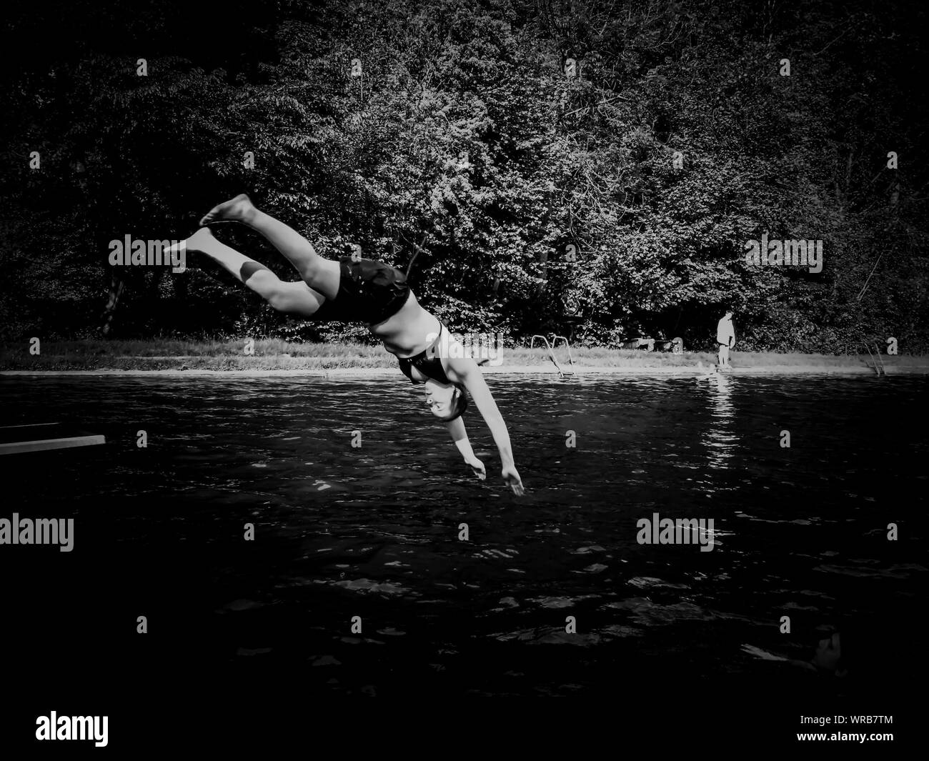 Three people jumping swimming pool Black and White Stock Photos ...