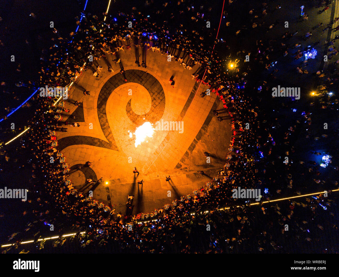 In this aerial view, Chinese people crowd around a bonfire at night to ...