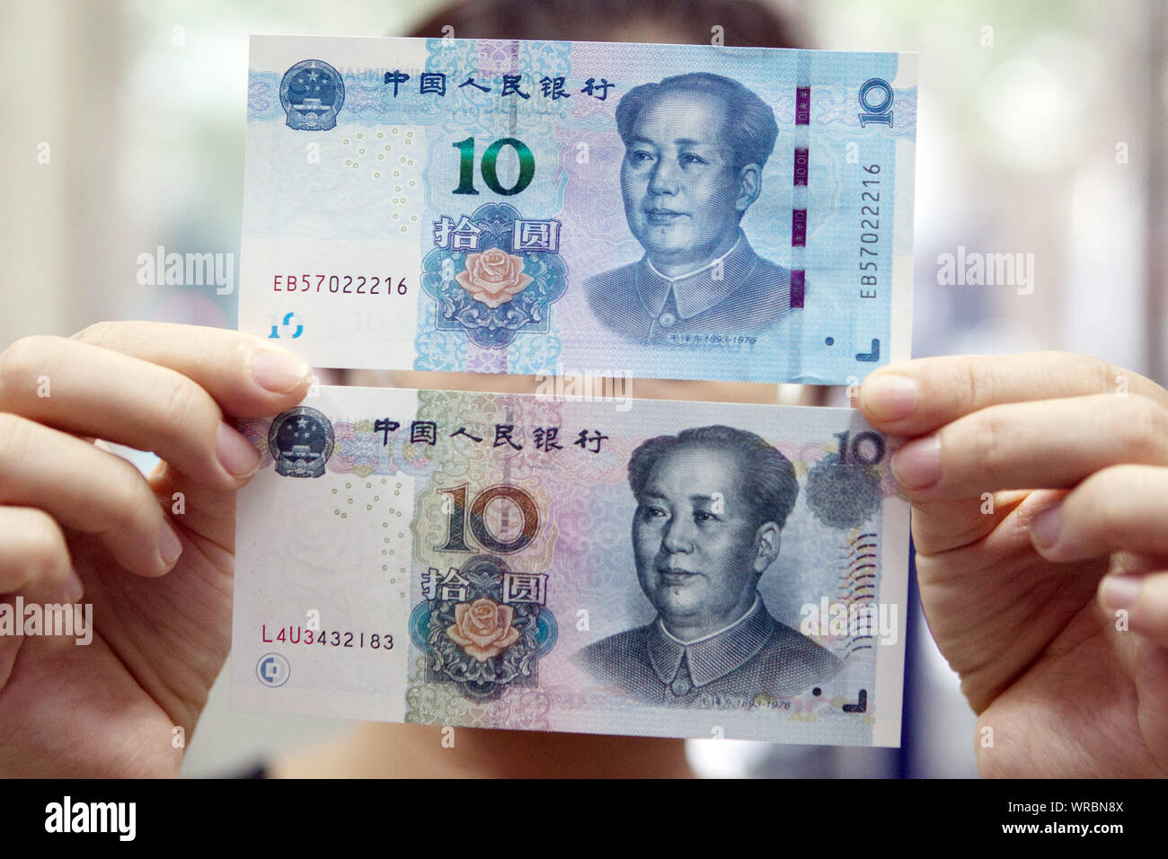A Chinese resident shows 10-yuan banknotes of the 2019 edition, top ...