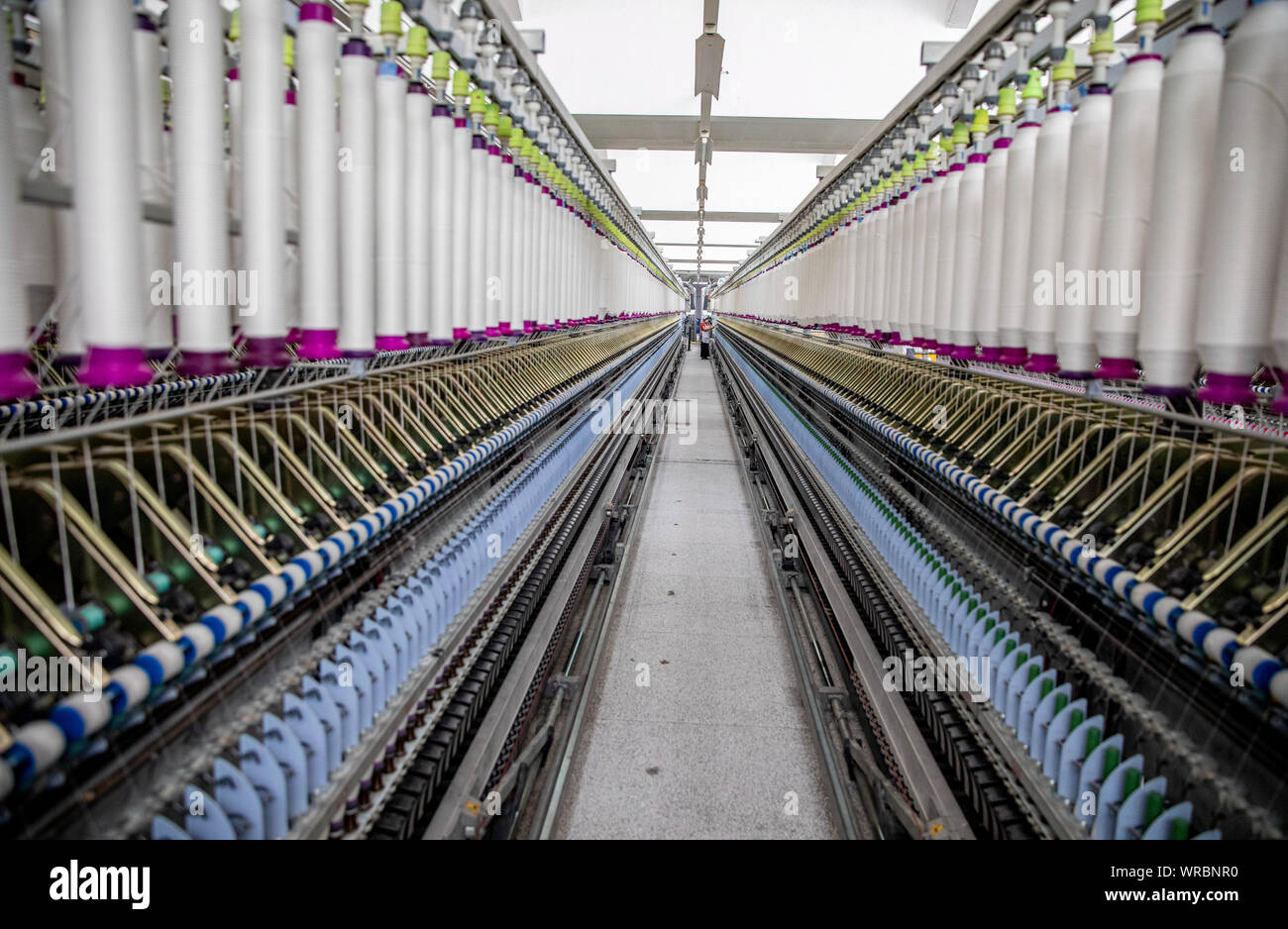 A female Chinese worker checks spindles of yarn on a spinning machine ...