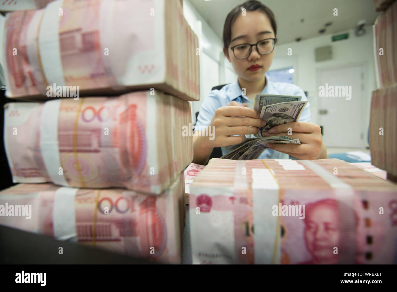 A female Chinese employee counts US dollar banknotes next to RMB ...