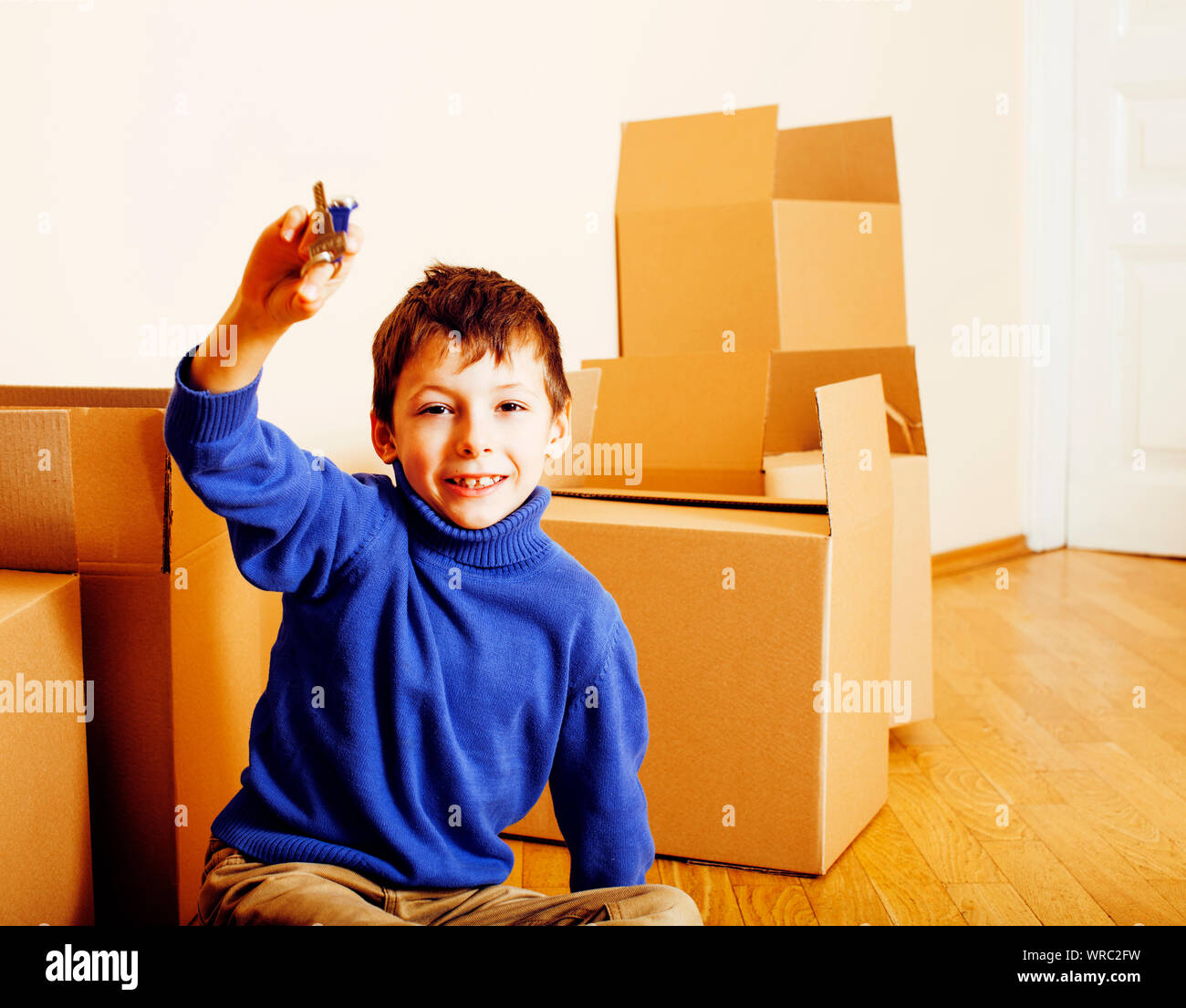 little cute boy in empty room with many boxes, remoove to new home ...