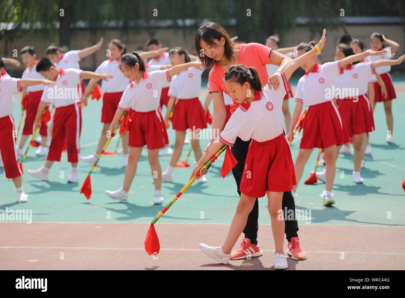Young Chinese students practice Bawangbian Dance or Rattle Stick Dance ...