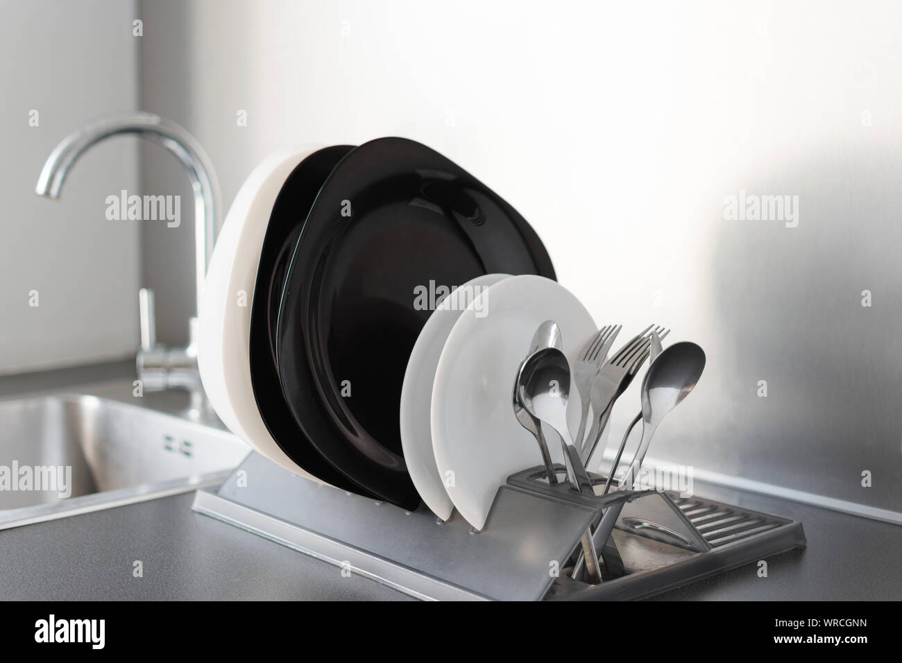 Set of fresh washed plates and cutlery on the kitchen gray table Stock ...