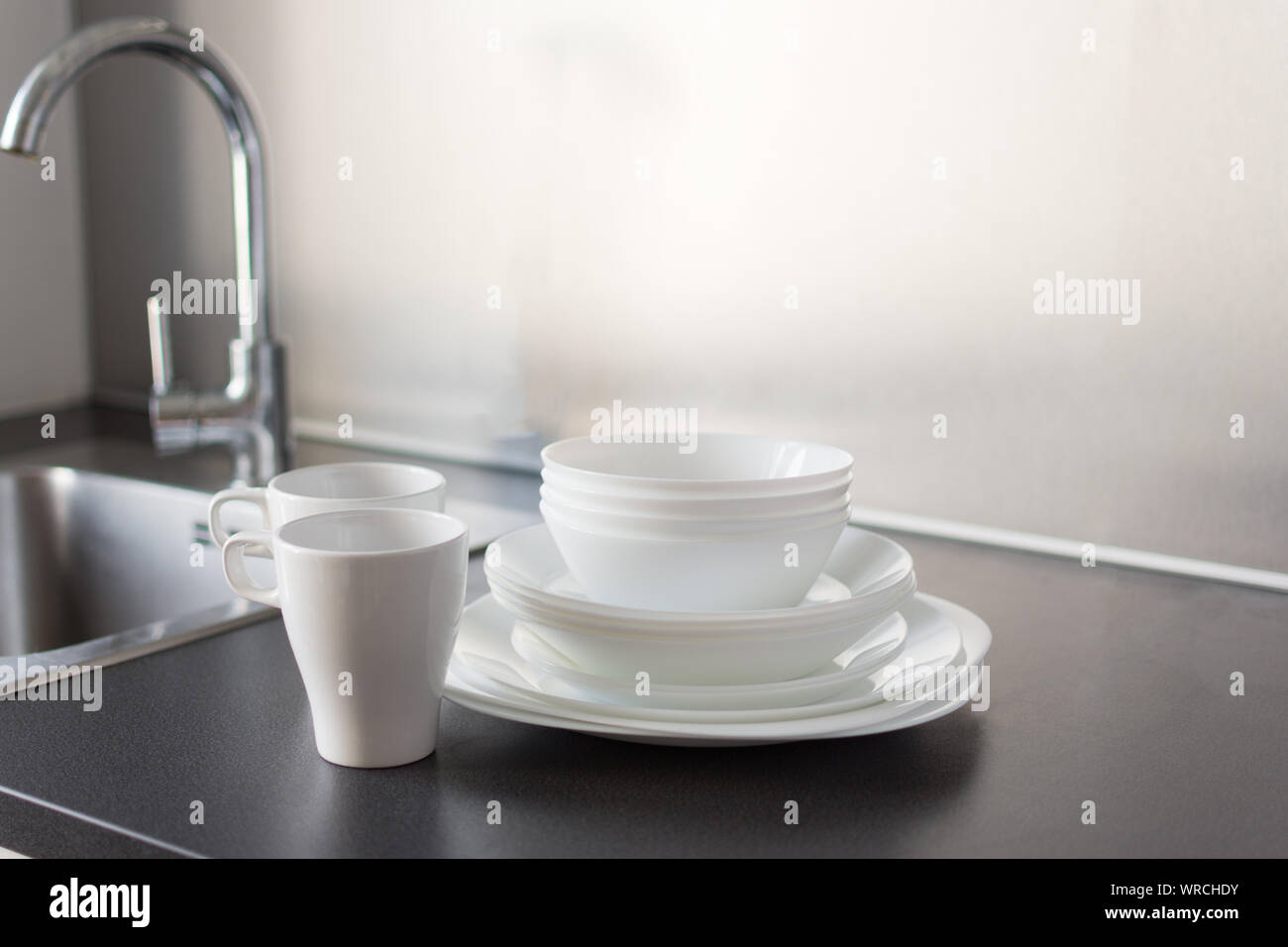 Set of fresh washed plates and cutlery on the kitchen gray table Stock ...