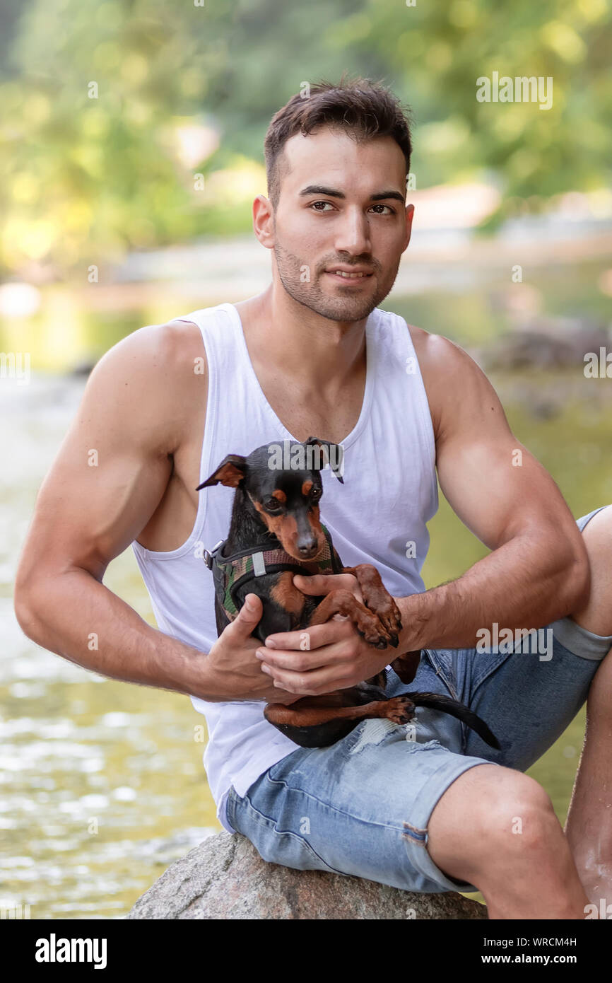 Close-up portrait of handsome young man with dog, outdoor Stock Photo ...