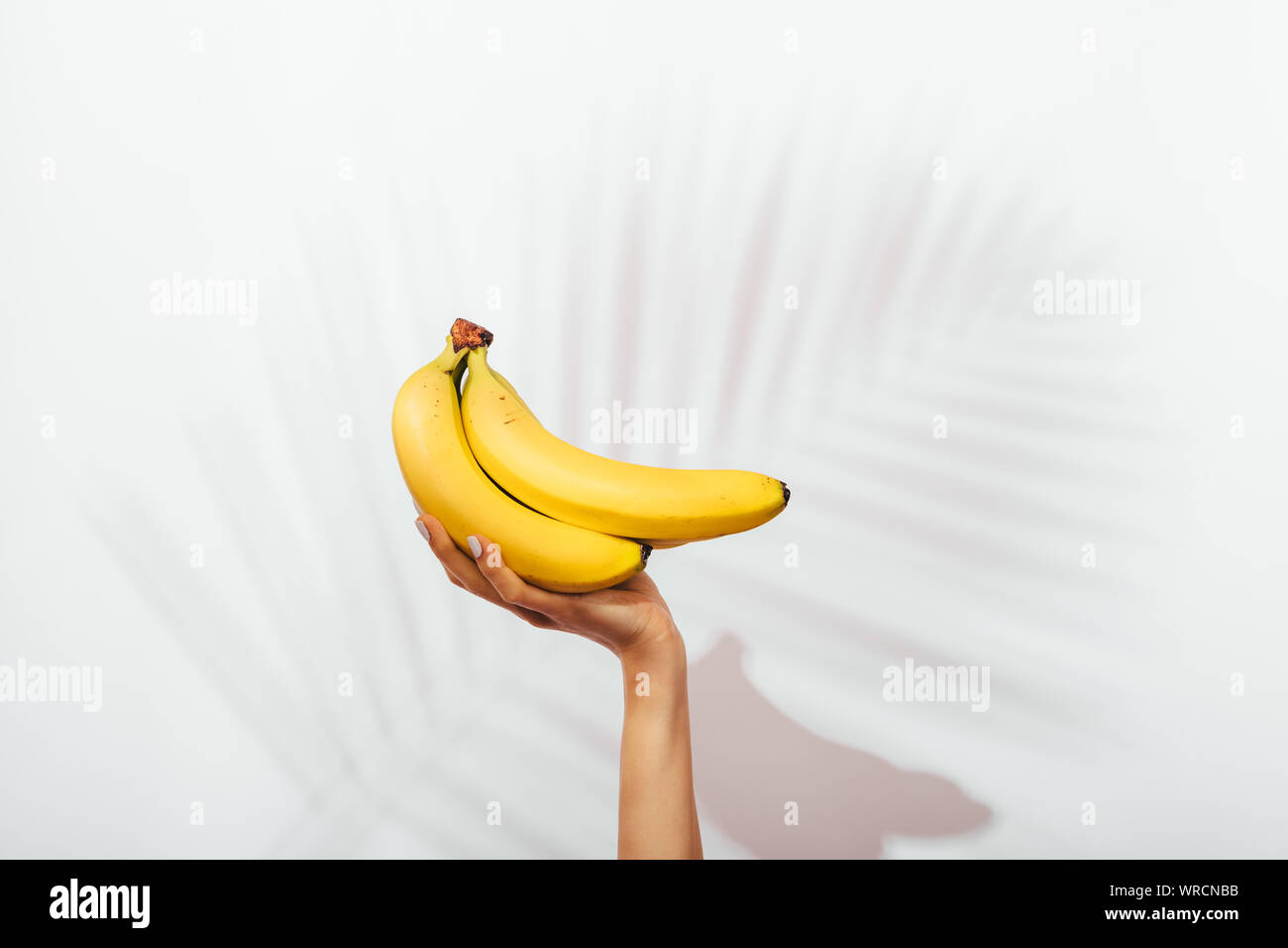 Bananas in a female hand on a white background Stock Photo - Alamy