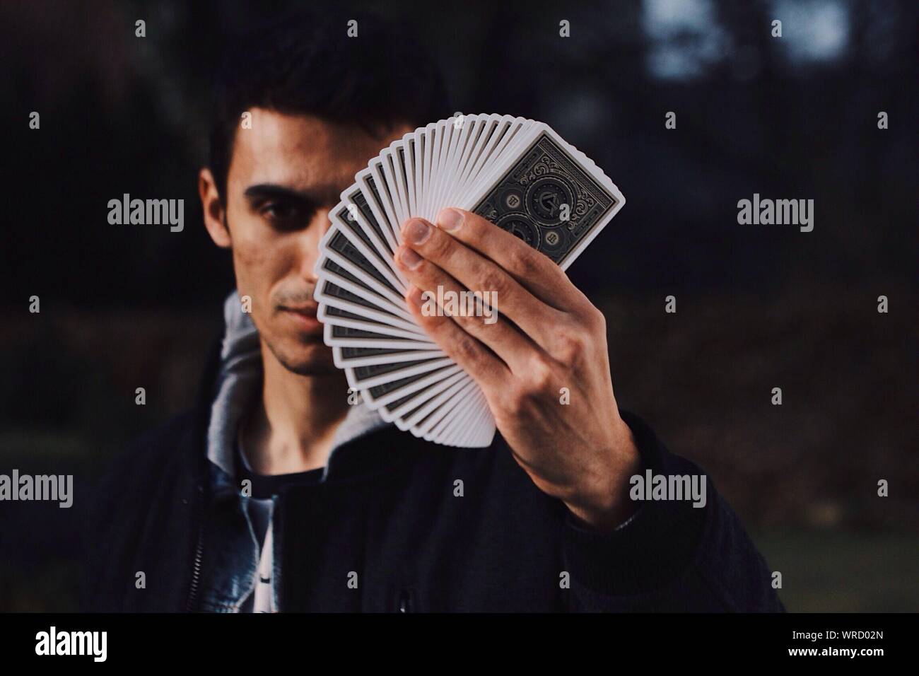 Young man holding playing card hi-res stock photography and images - Alamy
