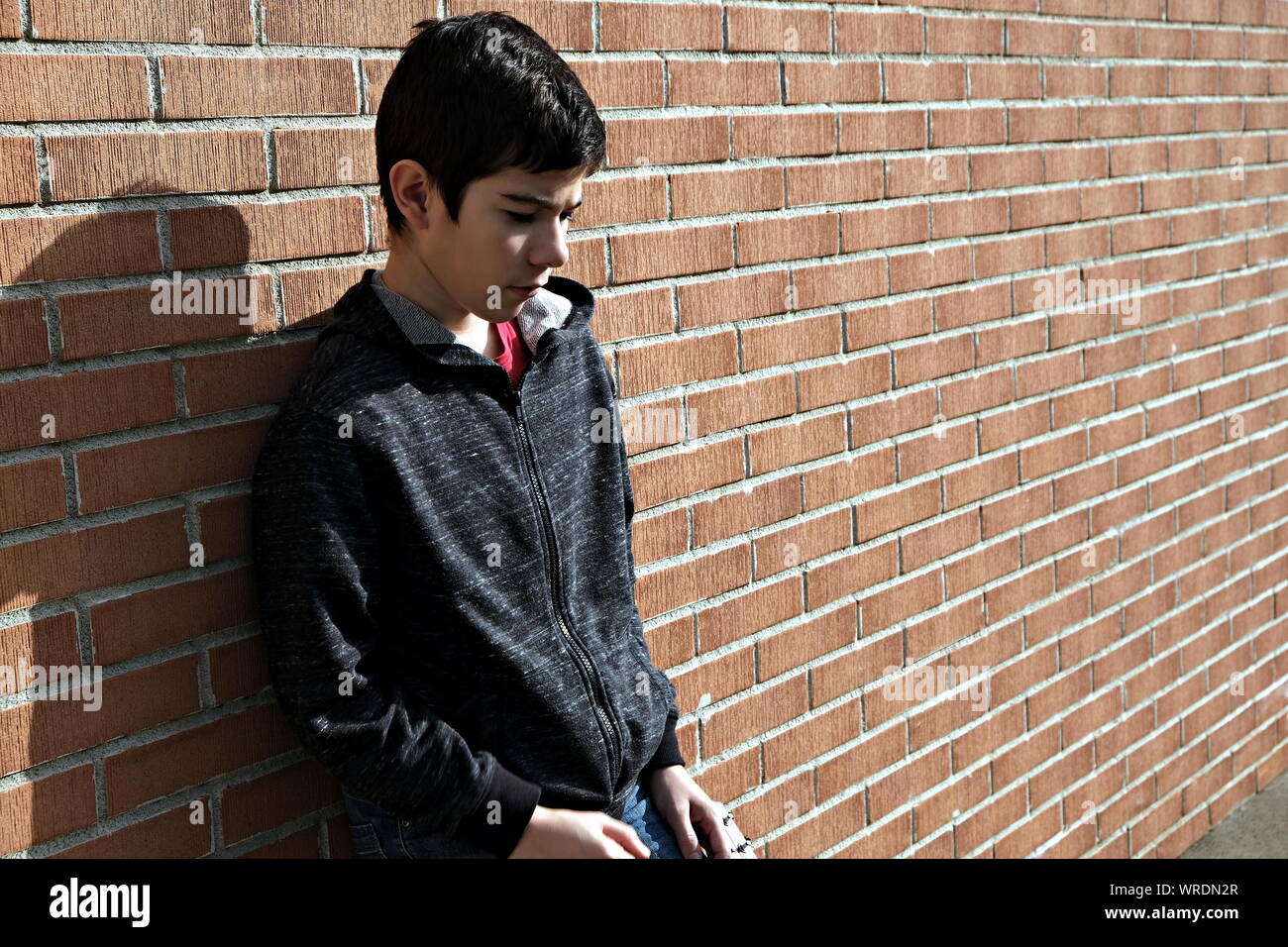 Sad teeanger leaning against a wall Stock Photo - Alamy