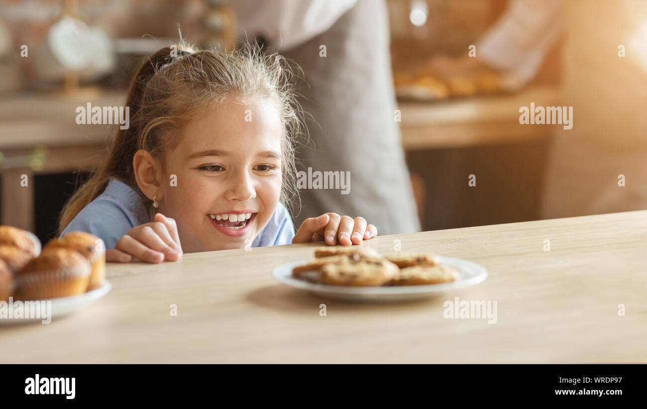 Adorable little girl looking at cookies with desire Stock Photo - Alamy