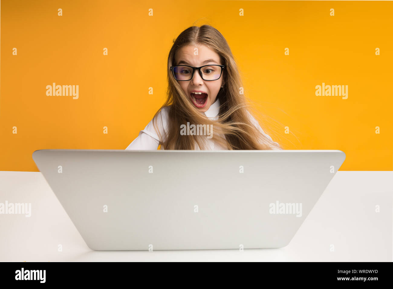 Overwhelmed Schoolgirl Using Laptop Over Yellow Background Stock Photo ...