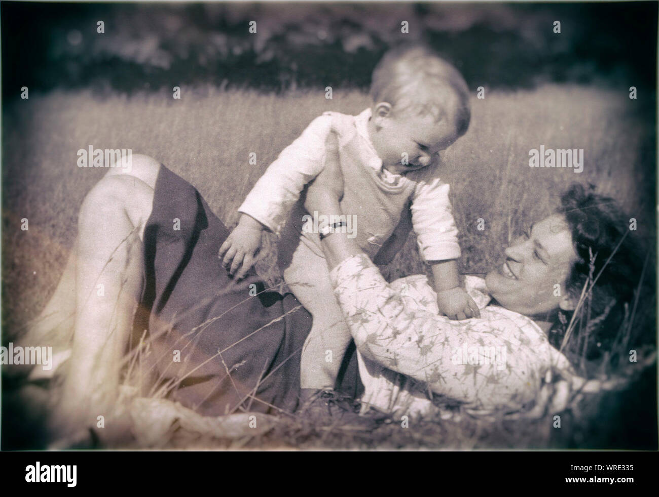 Poland, circa 1959:young mother with her baby boy playing in the grass ...