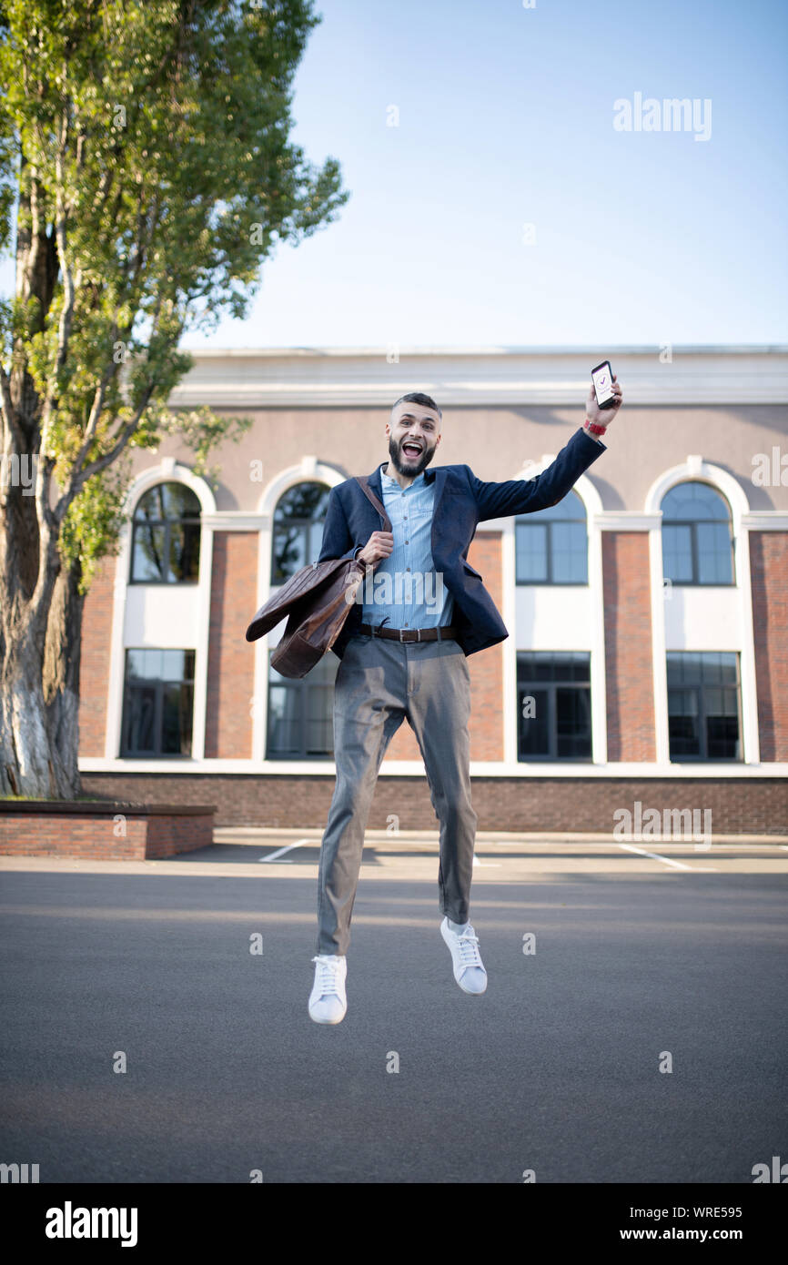 Businessman jumping while feeling happy after reading message Stock ...