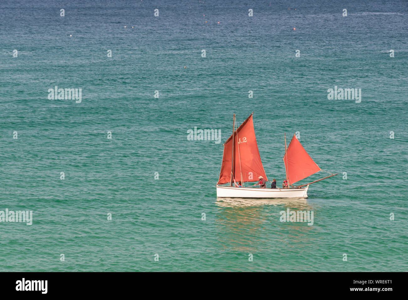 Sailing dinghy with red sails approaches the Harbour, St Ives, Cornwall ...