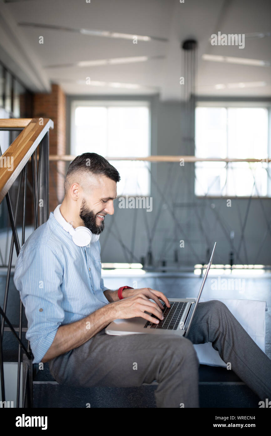 Smiling successful freelancer sitting on stairs and working Stock Photo ...