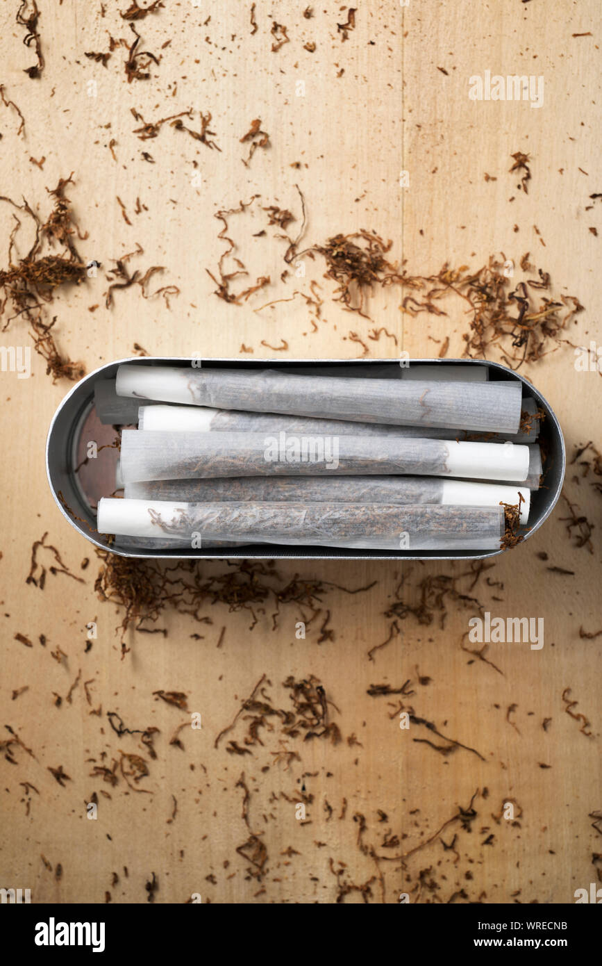Hand rolling tobacco on a wood table Stock Photo - Alamy