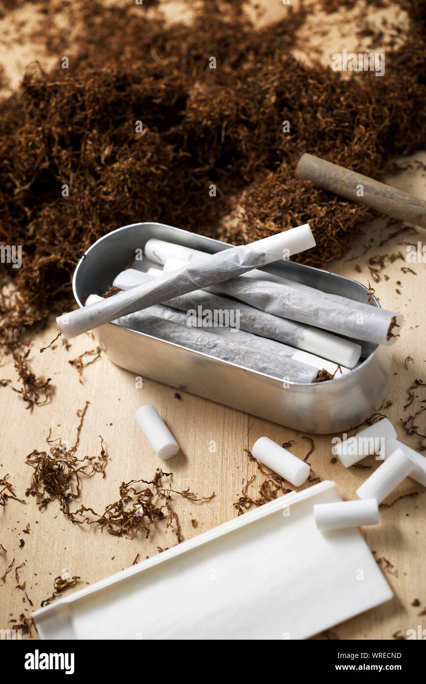Hand rolling tobacco on a wood table Stock Photo - Alamy