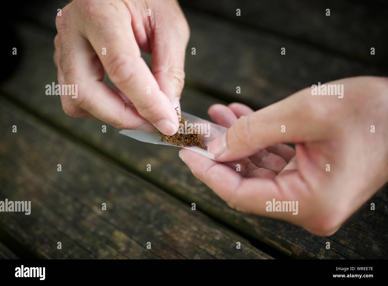 Hands of a man rolling a cigarette Stock Photo - Alamy