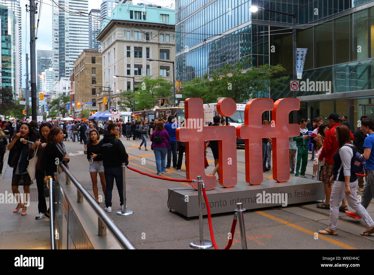 TIFF 2019 fans walk on King St West in Toronto next to the TIFF sign ...