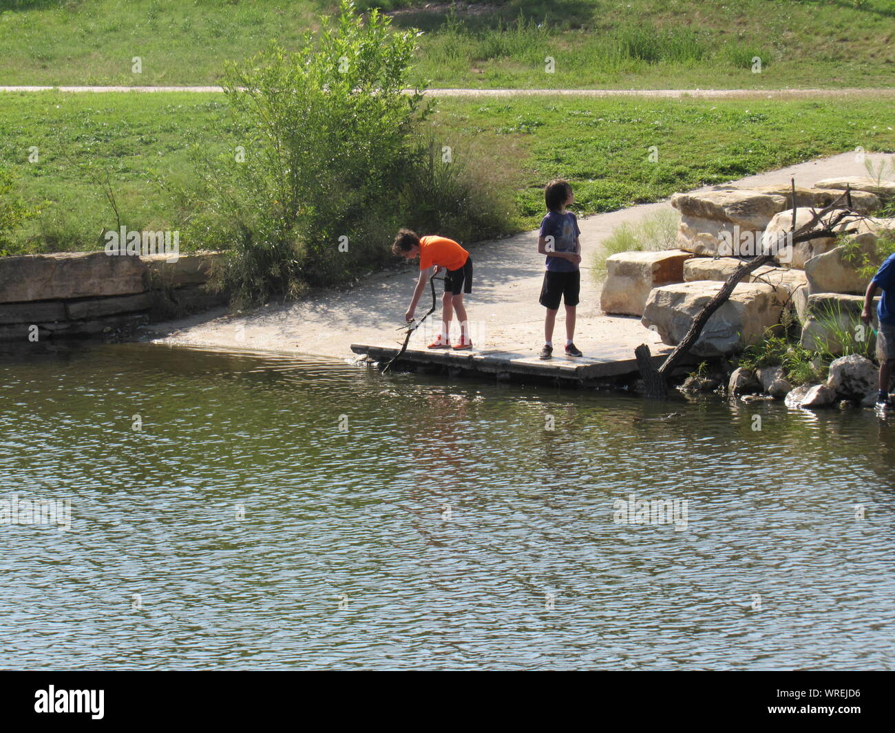 Two boys playing with a stick along the Concho River in San Angelo ...