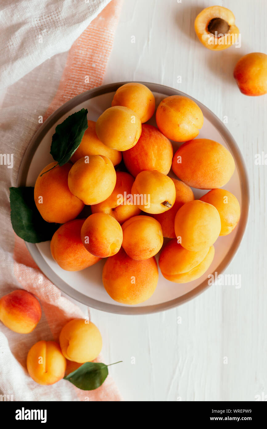 Delicious ripe organic apricots on a white plate and wooden table. Flat ...