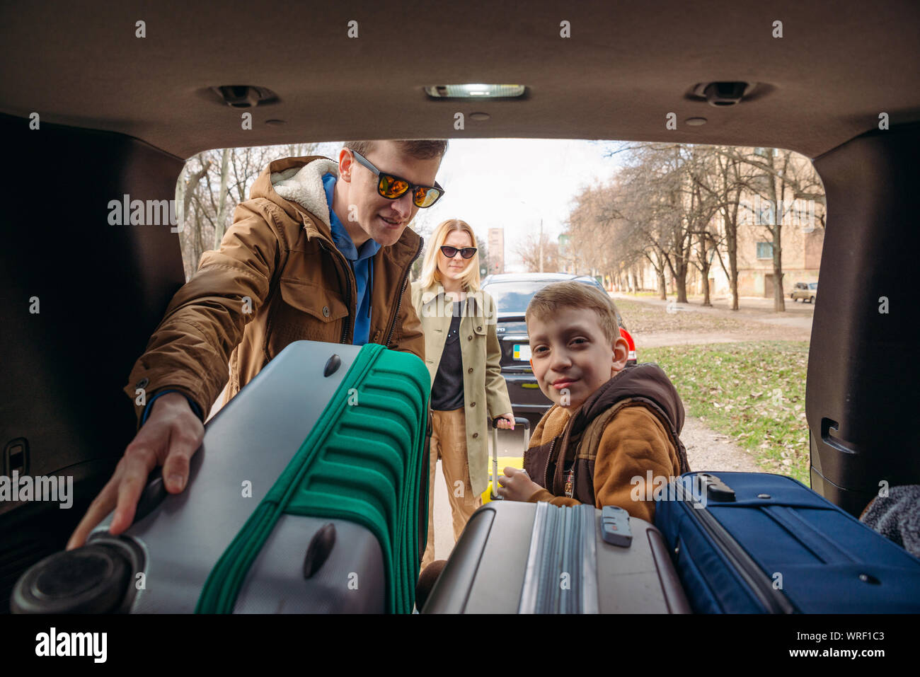 family with kid putting bag in car trunk Stock Photo - Alamy