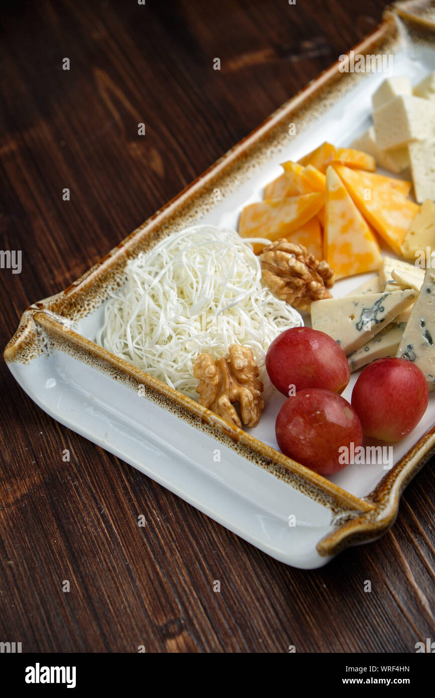 Beautiful table setting Cheese platter on a white plate on a dark ...