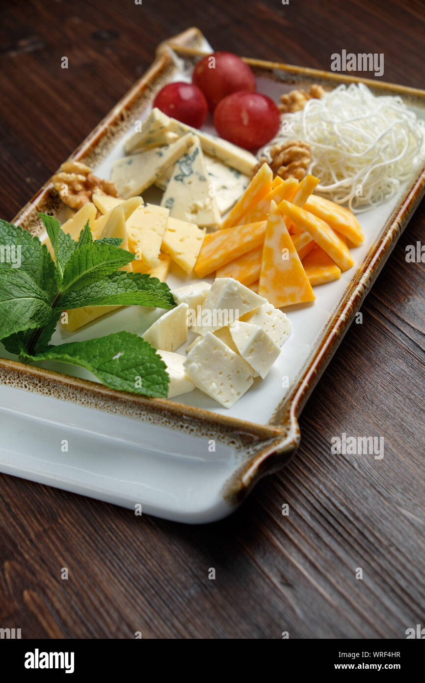 Beautiful table setting Cheese platter on a white plate on a dark ...