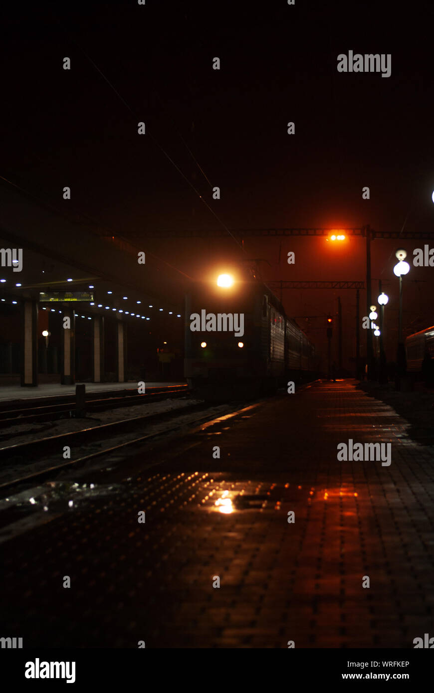 Passenger train on the platform of the dark railway station at night ...
