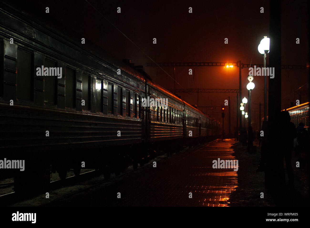 Passenger train on the platform of the dark railway station at night ...