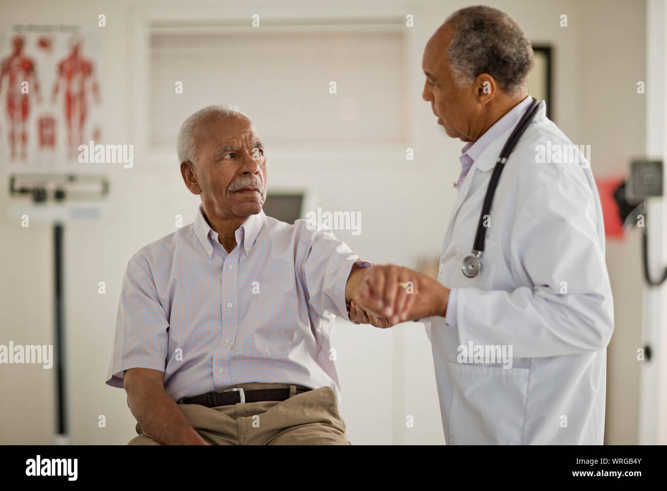 Senior man having his arm examined by a male doctor inside a doctor's ...