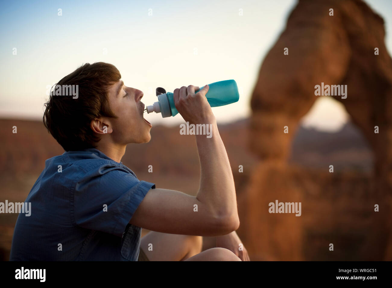 Young man drinking water from a bottle while in the desert Stock Photo ...