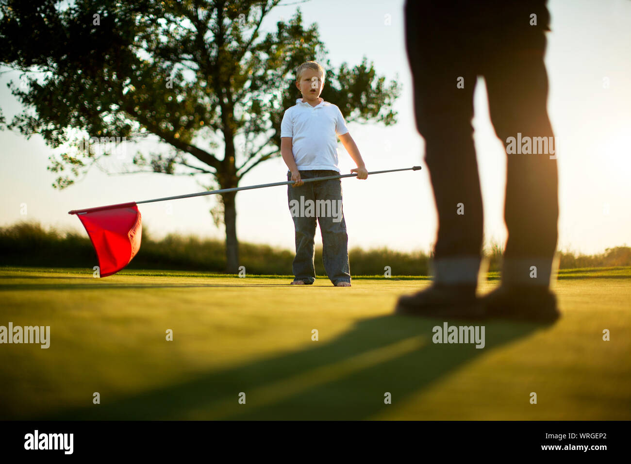 Young boy holding a flagpole on a golf course Stock Photo - Alamy
