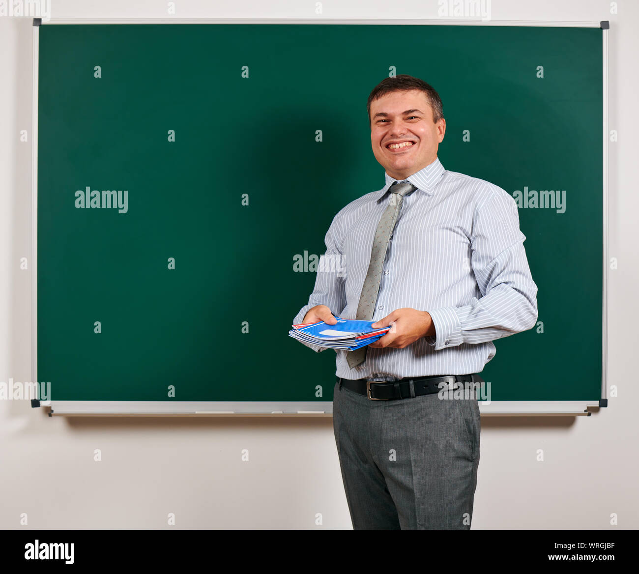 Portrait of a man as a teacher, posing at school board background ...