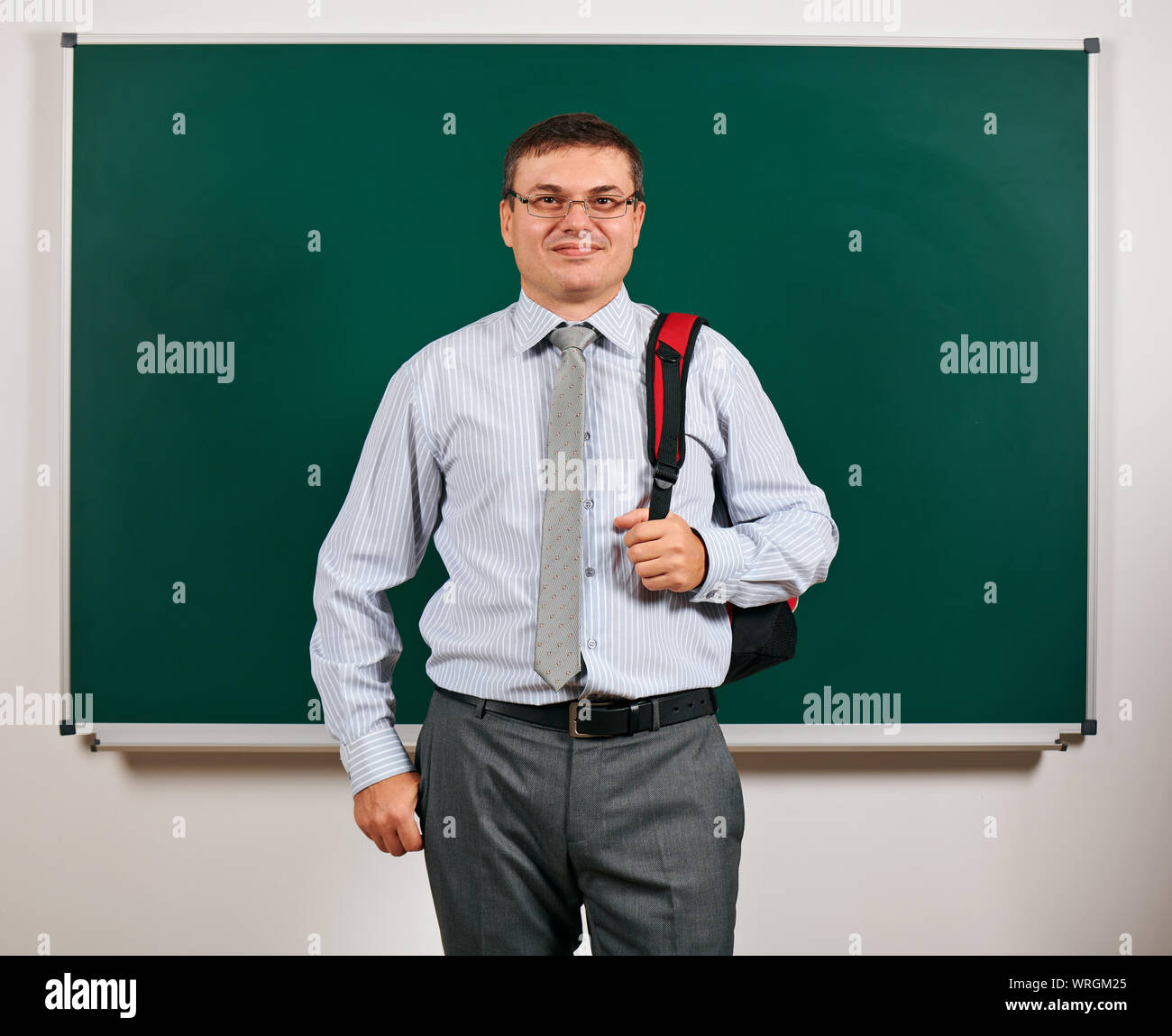 Portrait of a man as a teacher, posing at school board background ...