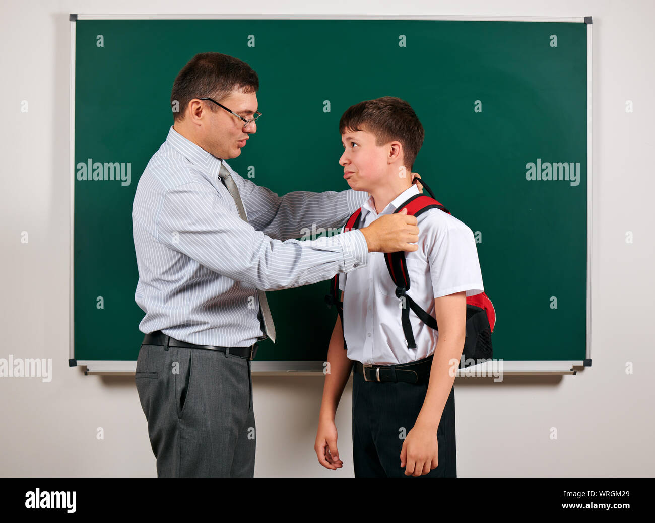 Portrait of a teacher and schoolboy playing at blackboard background ...