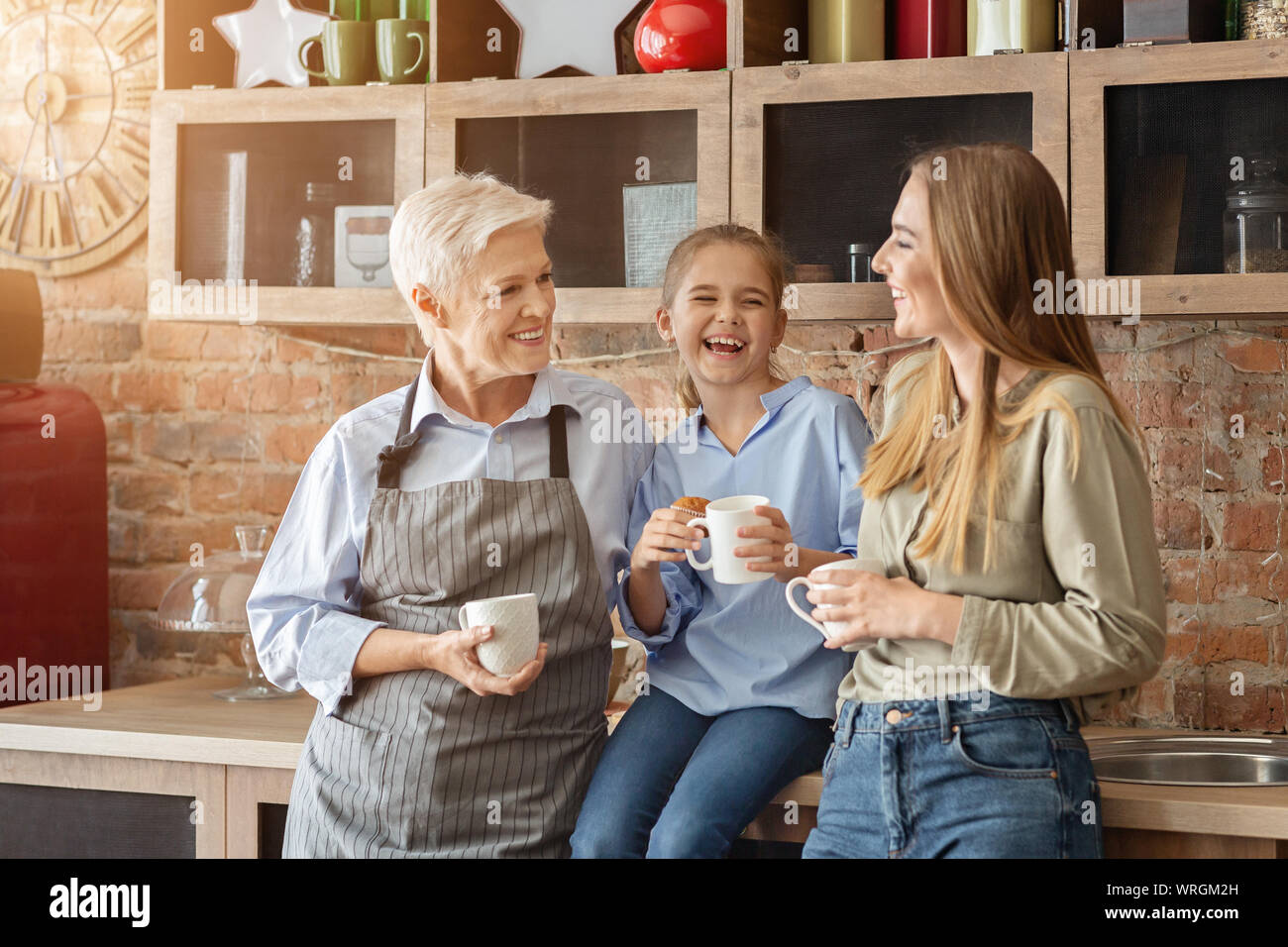Female family drinking tea and laughing at kitchen Stock Photo - Alamy