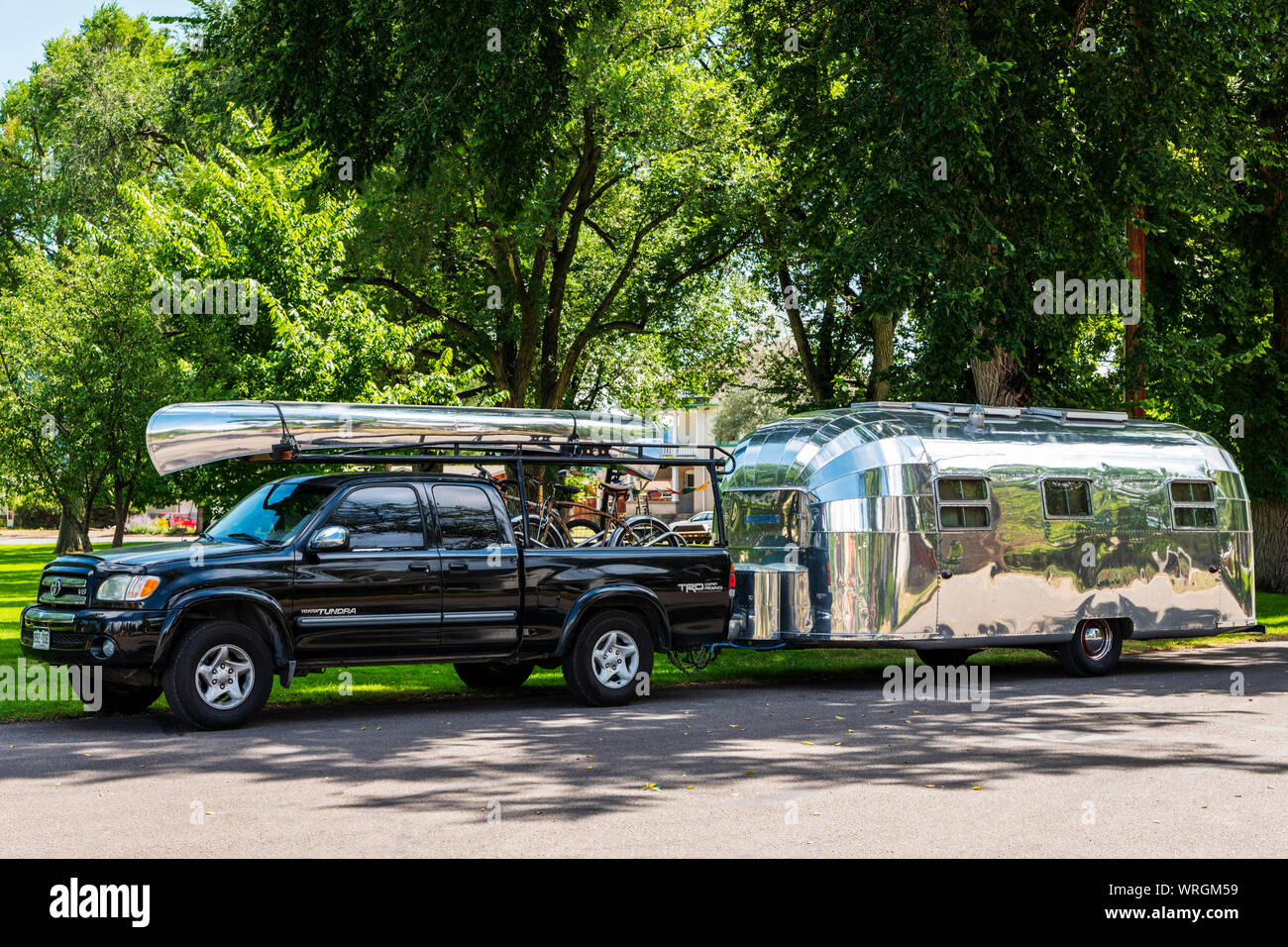 Pick-up truck with silver canoe pulling a matching silver Airstream ...