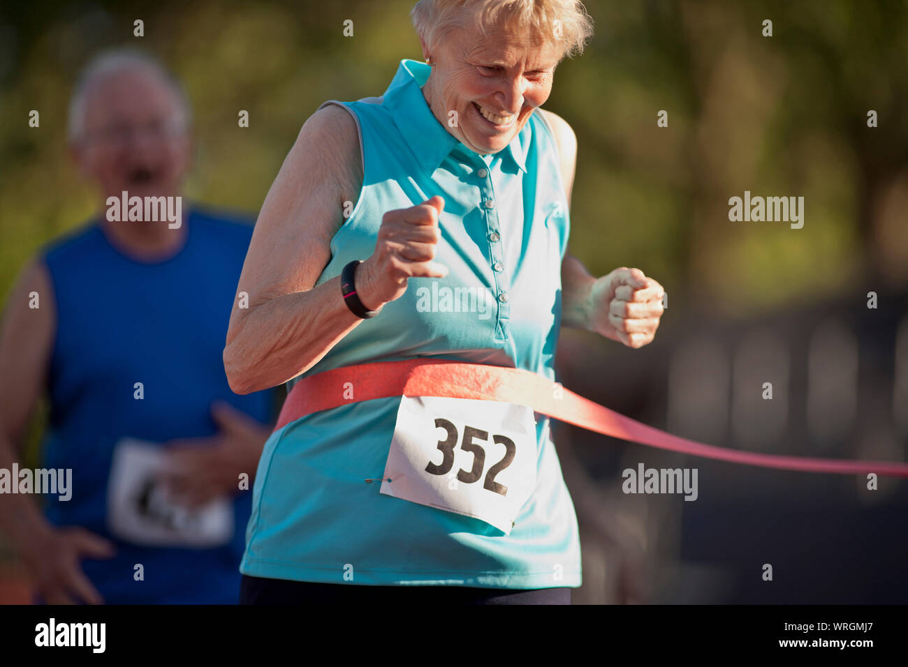 Smiling senior woman crossing the finish line of a running race Stock ...