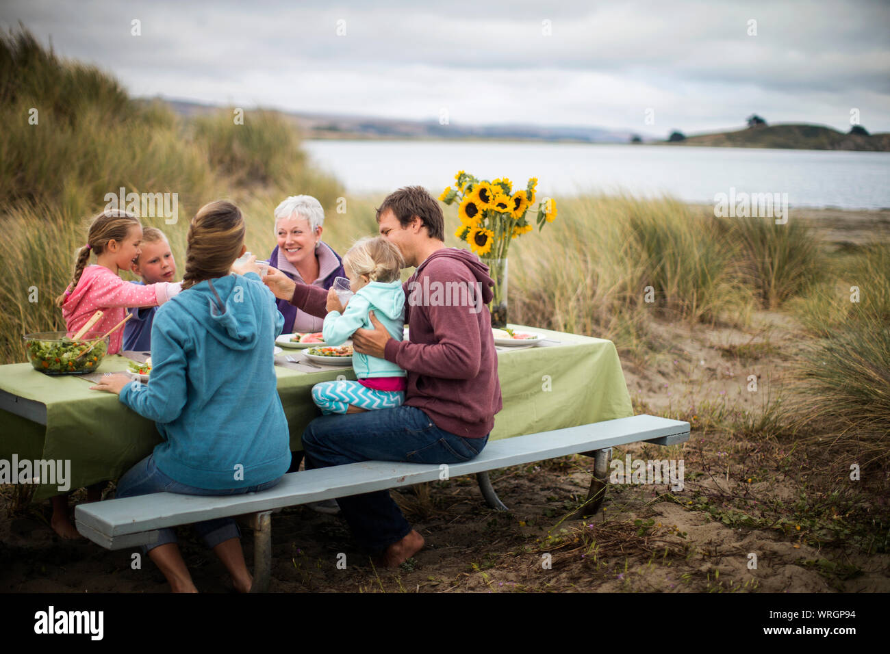 Happy multi-generational family enjoy an outdoor lunch at the beach ...