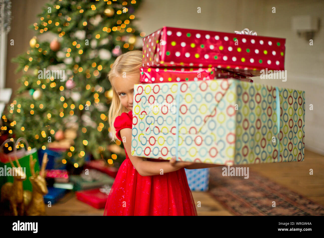 Young girl carrying a stack of Christmas presents Stock Photo - Alamy