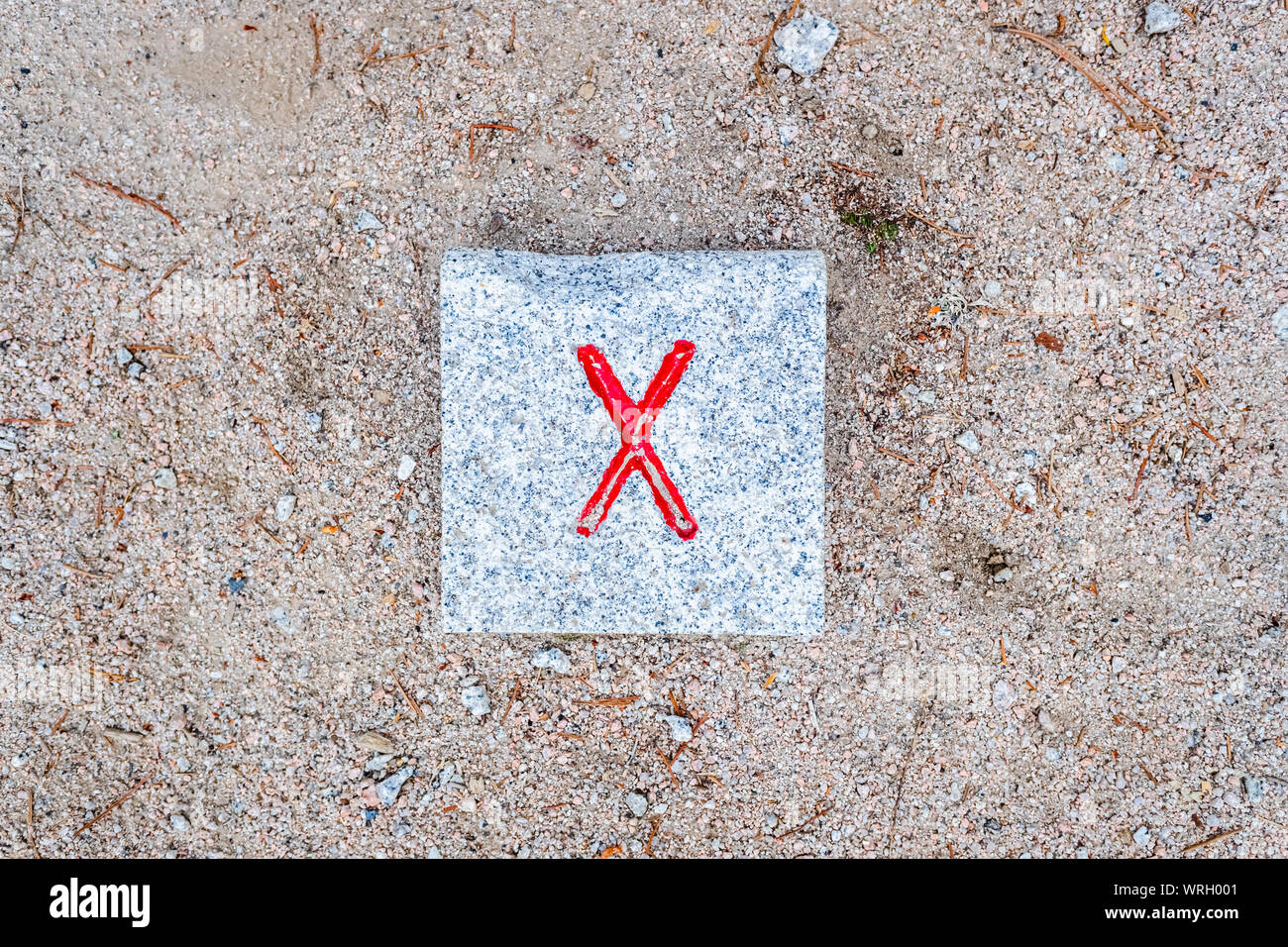 Mark X on a rock in the ground, indicating an important starting or ...