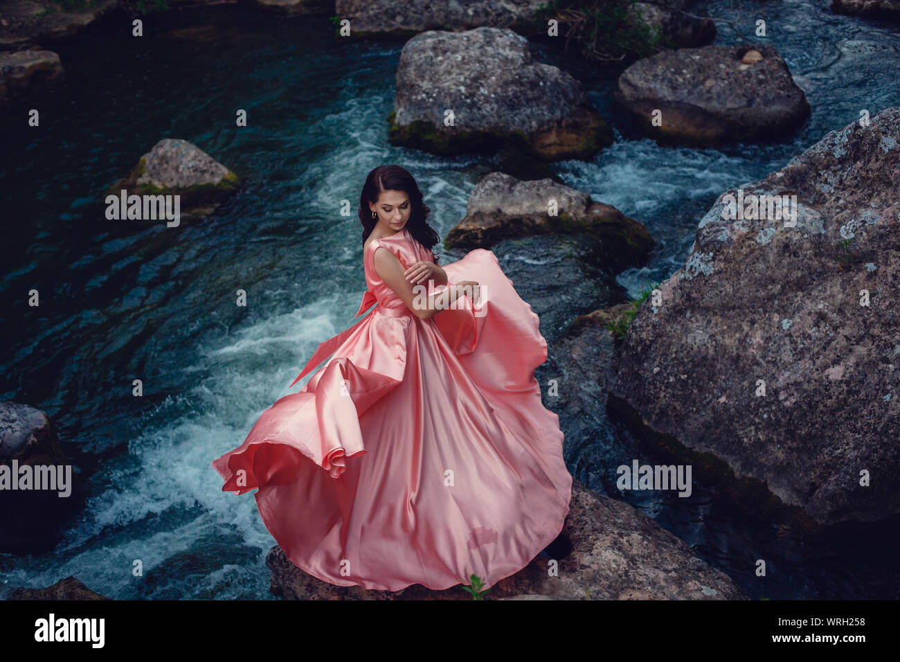 River witch, sitting on a rock in river. Pink long dress, a fabulous ...