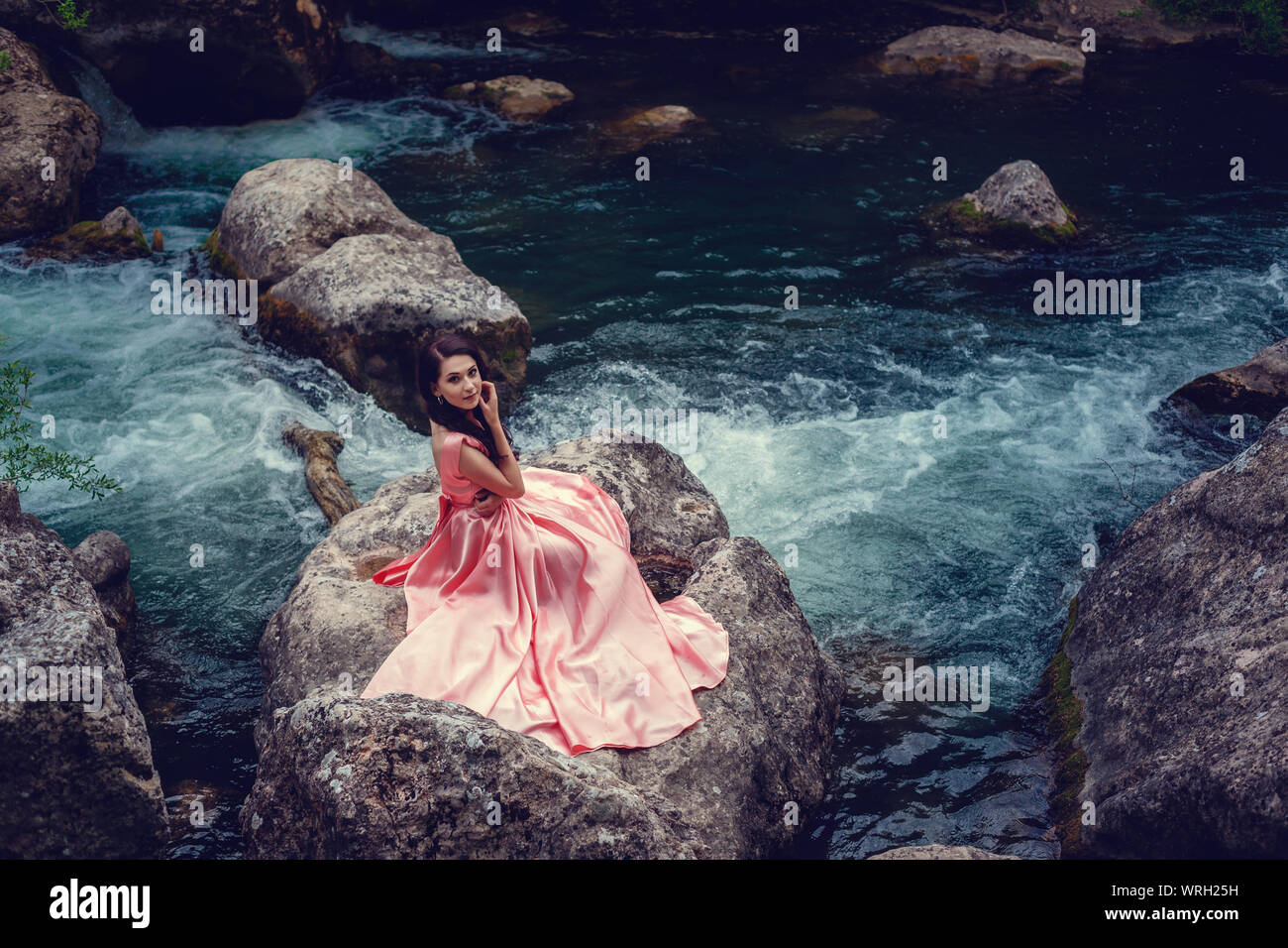 River witch, sitting on a rock in river. Pink long dress, a fabulous ...