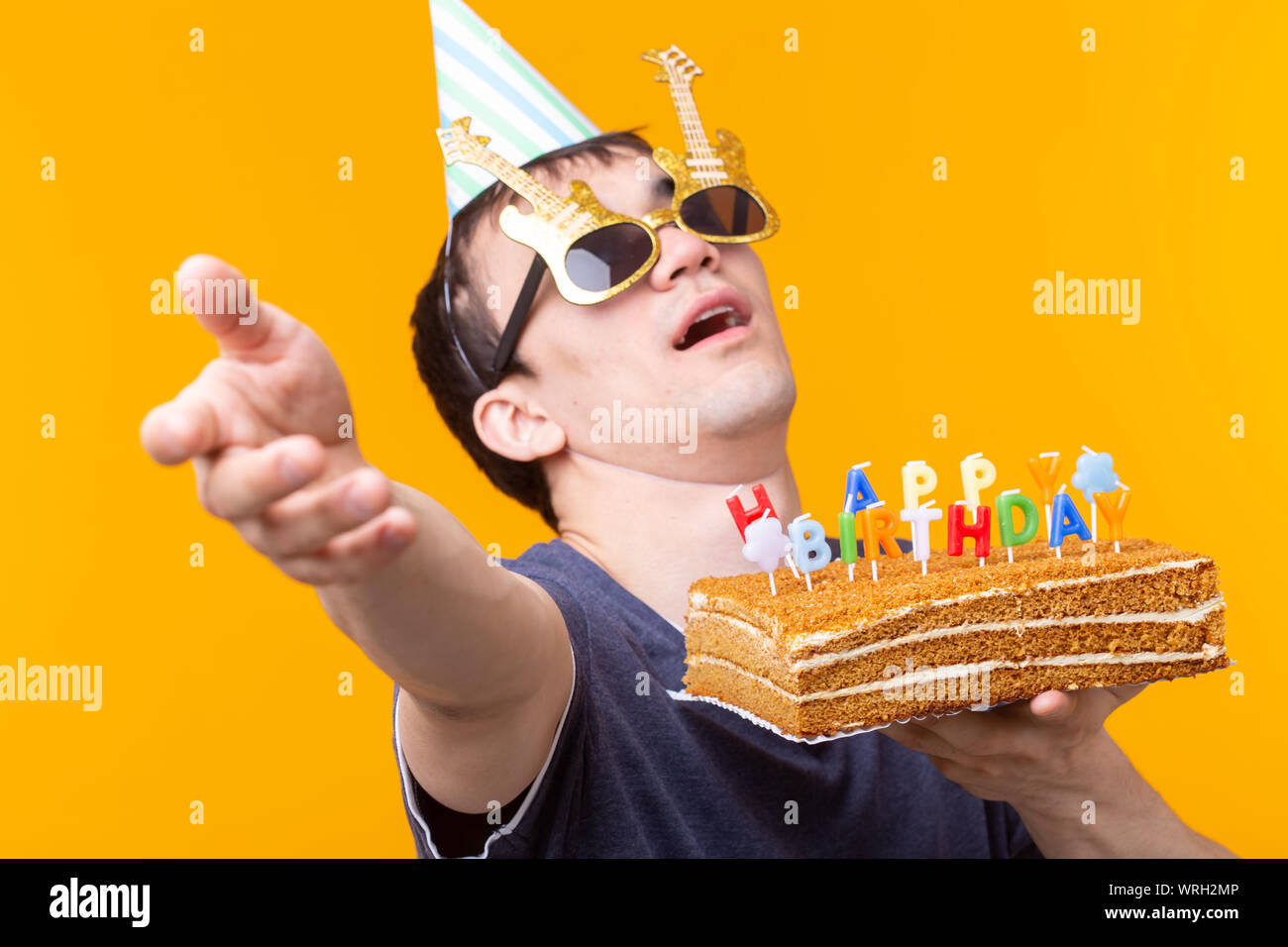 Crazy cheerful young man in glasses and paper congratulatory hats ...