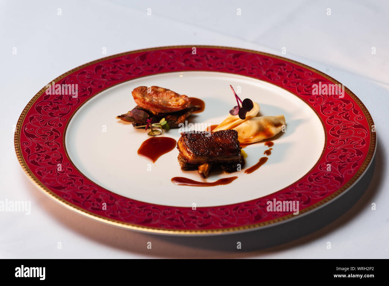 Fancy meat dinner on a red and white plate still life Stock Photo - Alamy