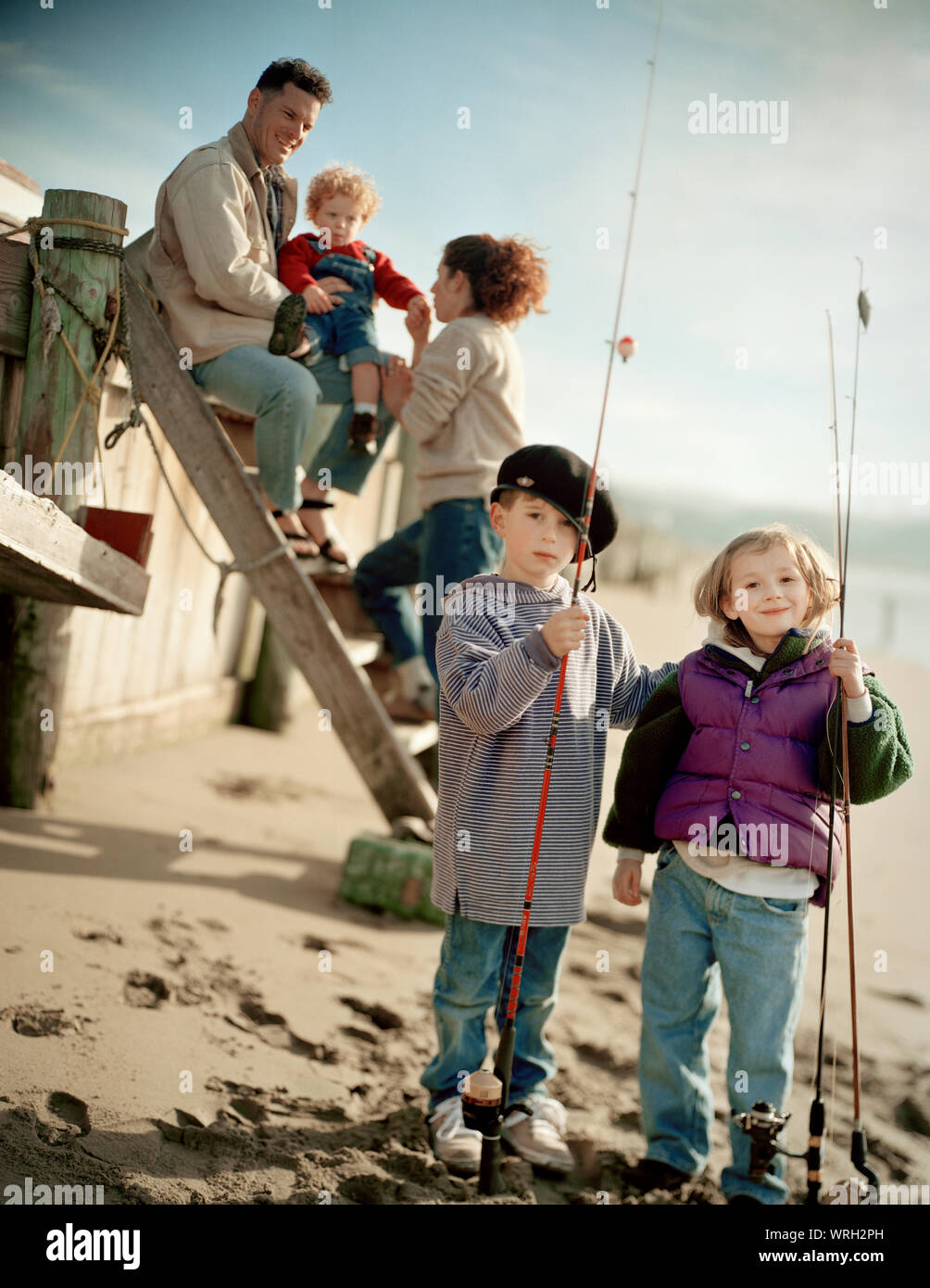 Portrait of a young brother and sister holding fishing rods while at ...